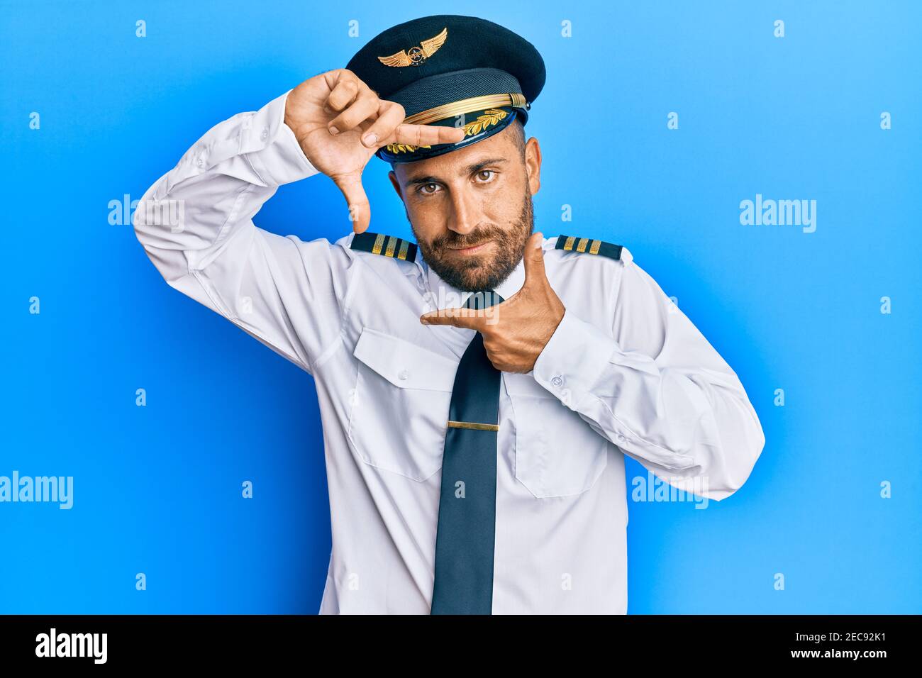 Handsome man with beard wearing airplane pilot uniform smiling making ...
