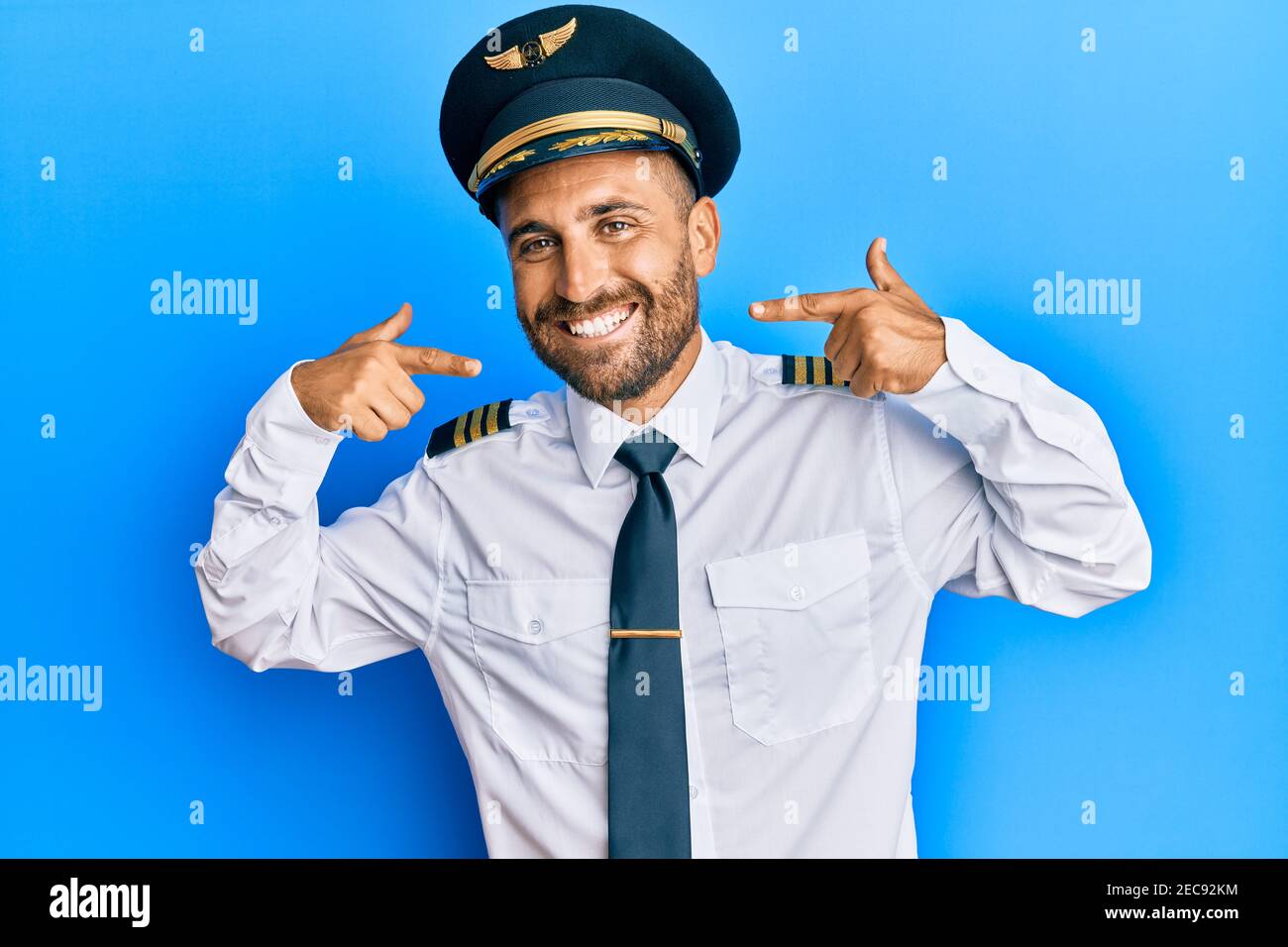 Handsome man with beard wearing airplane pilot uniform smiling cheerful ...
