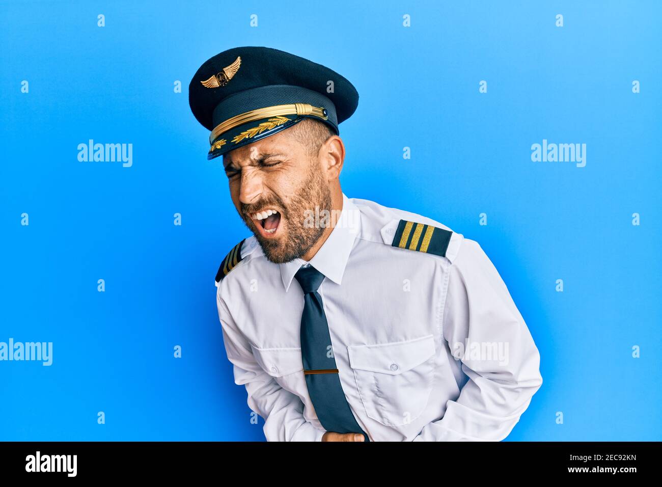 Handsome man with beard wearing airplane pilot uniform with hand on ...