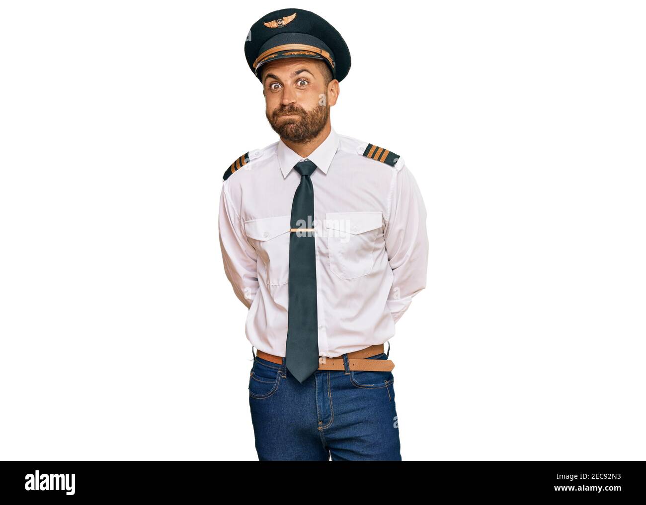 Handsome man with beard wearing airplane pilot uniform puffing cheeks ...