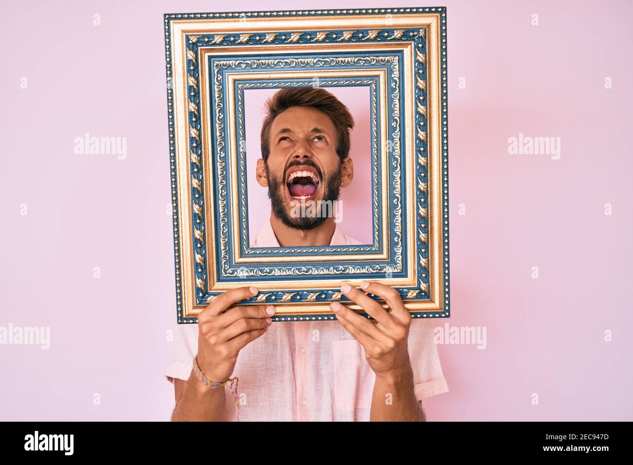 Handsome caucasian man with beard holding empty frame angry and mad ...