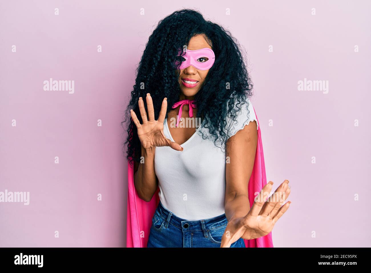 Middle age african american woman wearing super hero costume afraid and ...