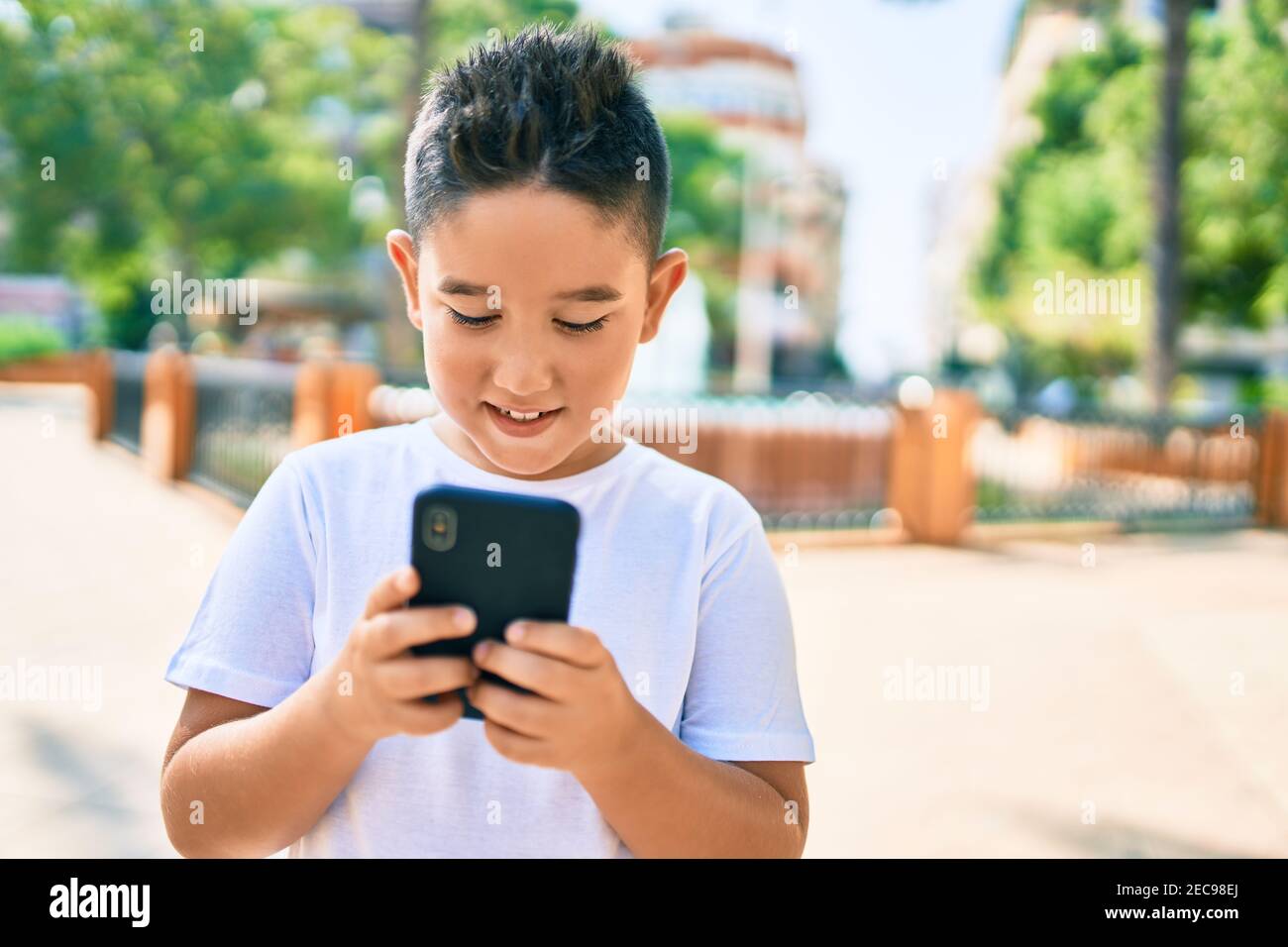 Adorable boy smiling happy using smartphone at street of city Stock ...