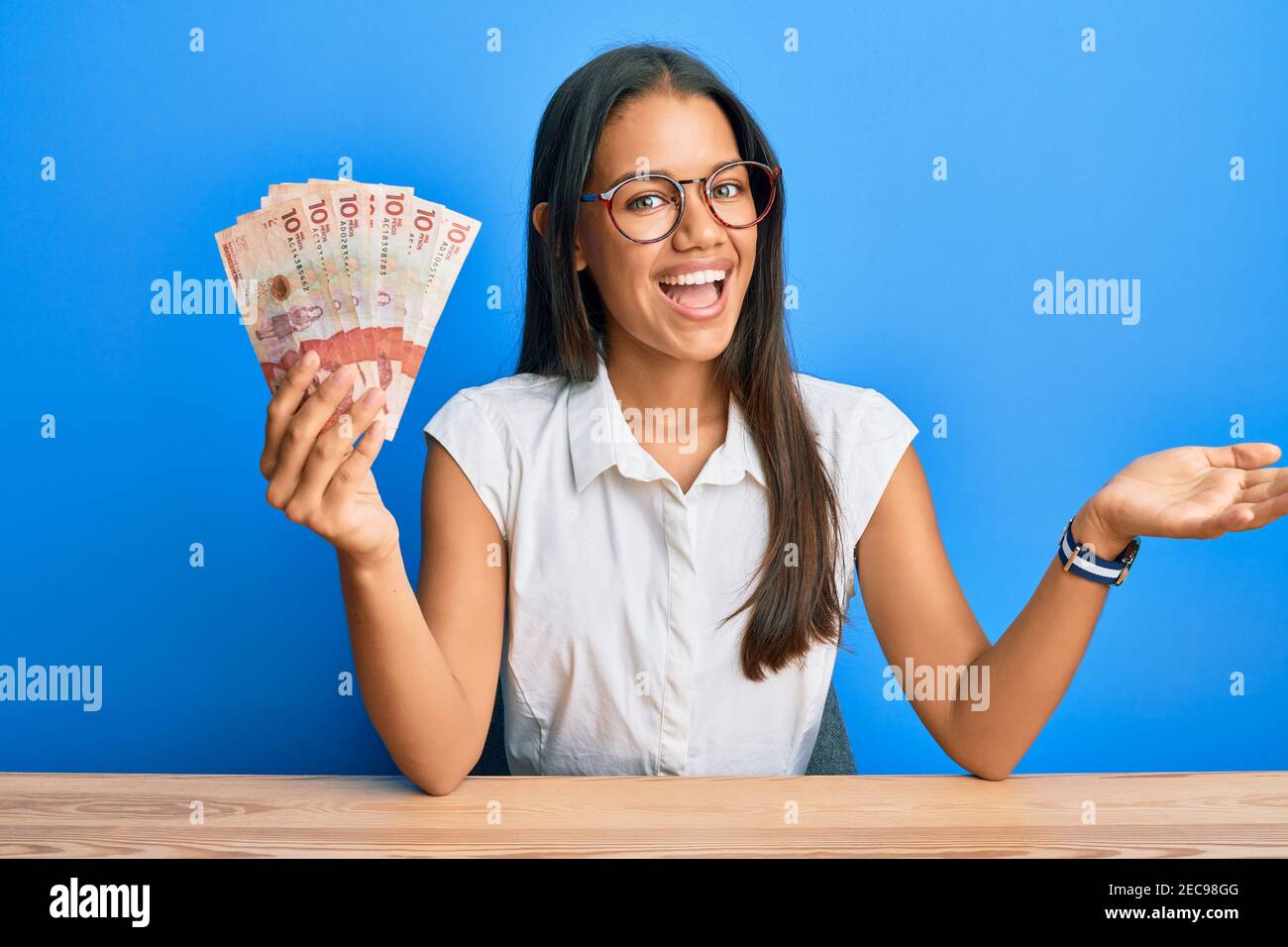 Beautiful hispanic woman holding 10 united kingdom pounds banknotes ...