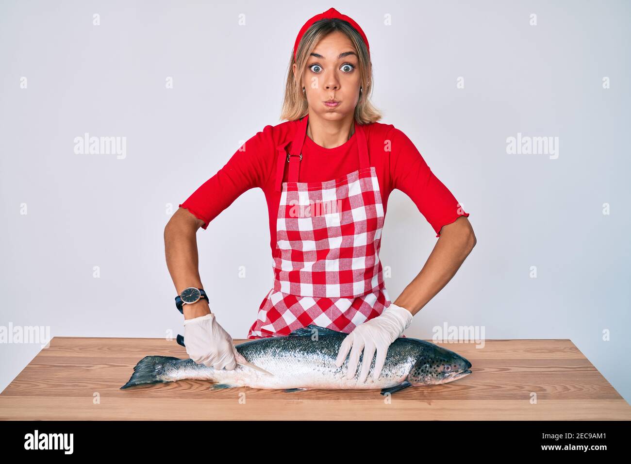 Beautiful caucasian woman fishmonger selling fresh raw salmon puffing ...