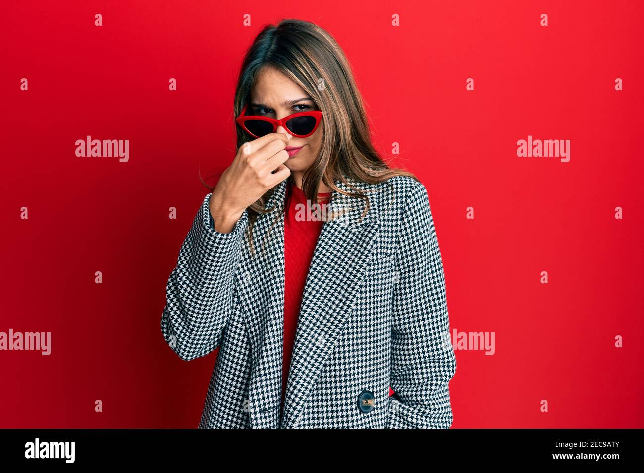 Young brunette woman wearing fashion and modern look smelling something ...