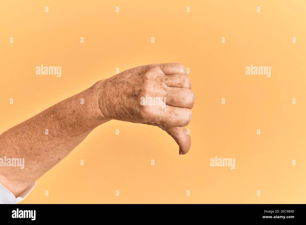 Senior caucasian hand over yellow isolated background doing thumbs down ...