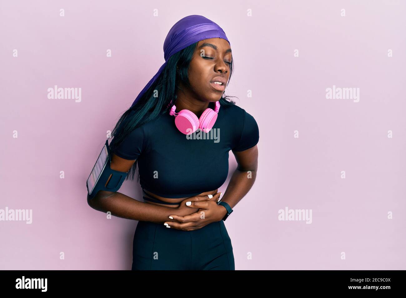 Young african american woman wearing gym clothes and using headphones ...