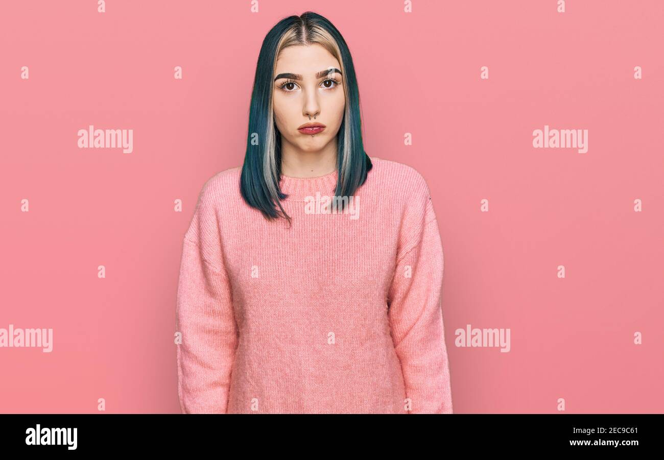 Young modern girl wearing pink wool winter sweater depressed and worry ...