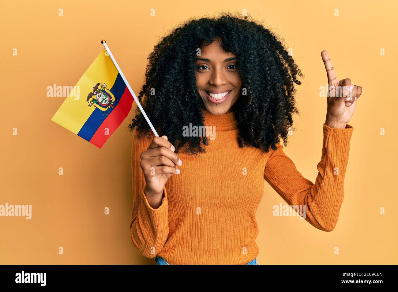 African american woman with afro hair holding ecuador flag smiling with ...