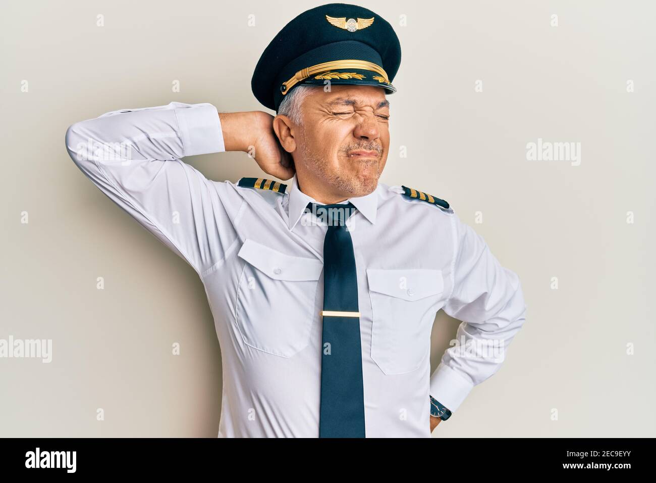 Handsome middle age mature man wearing airplane pilot uniform suffering ...