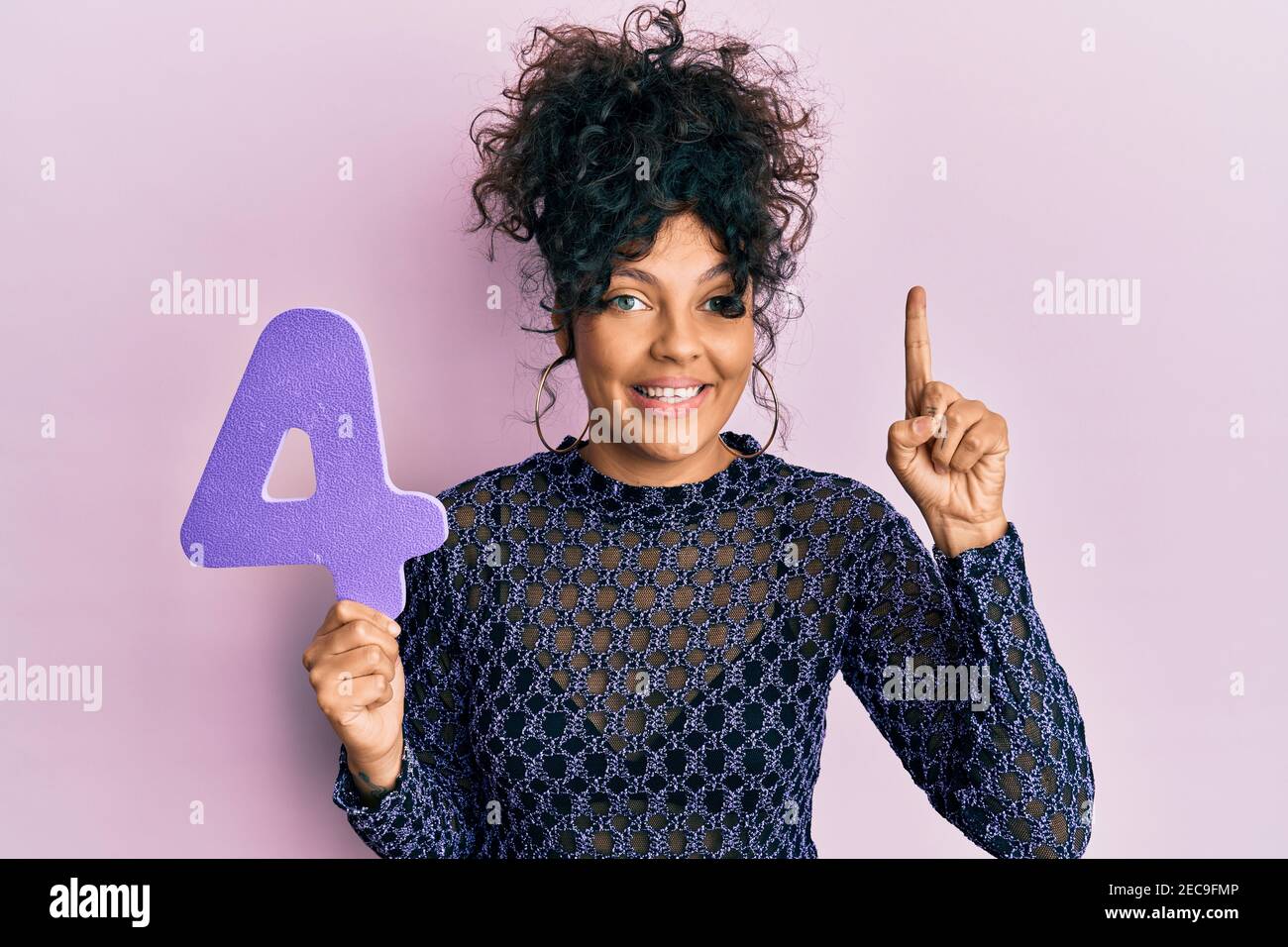 Young hispanic woman holding number four smiling with an idea or ...