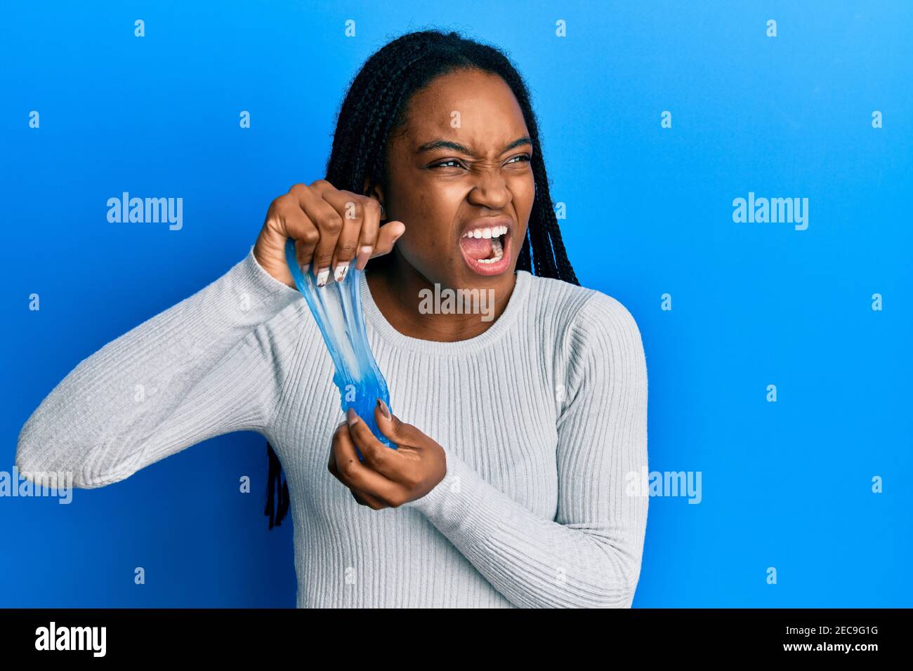 African american woman with braided hair holding slime angry and mad ...