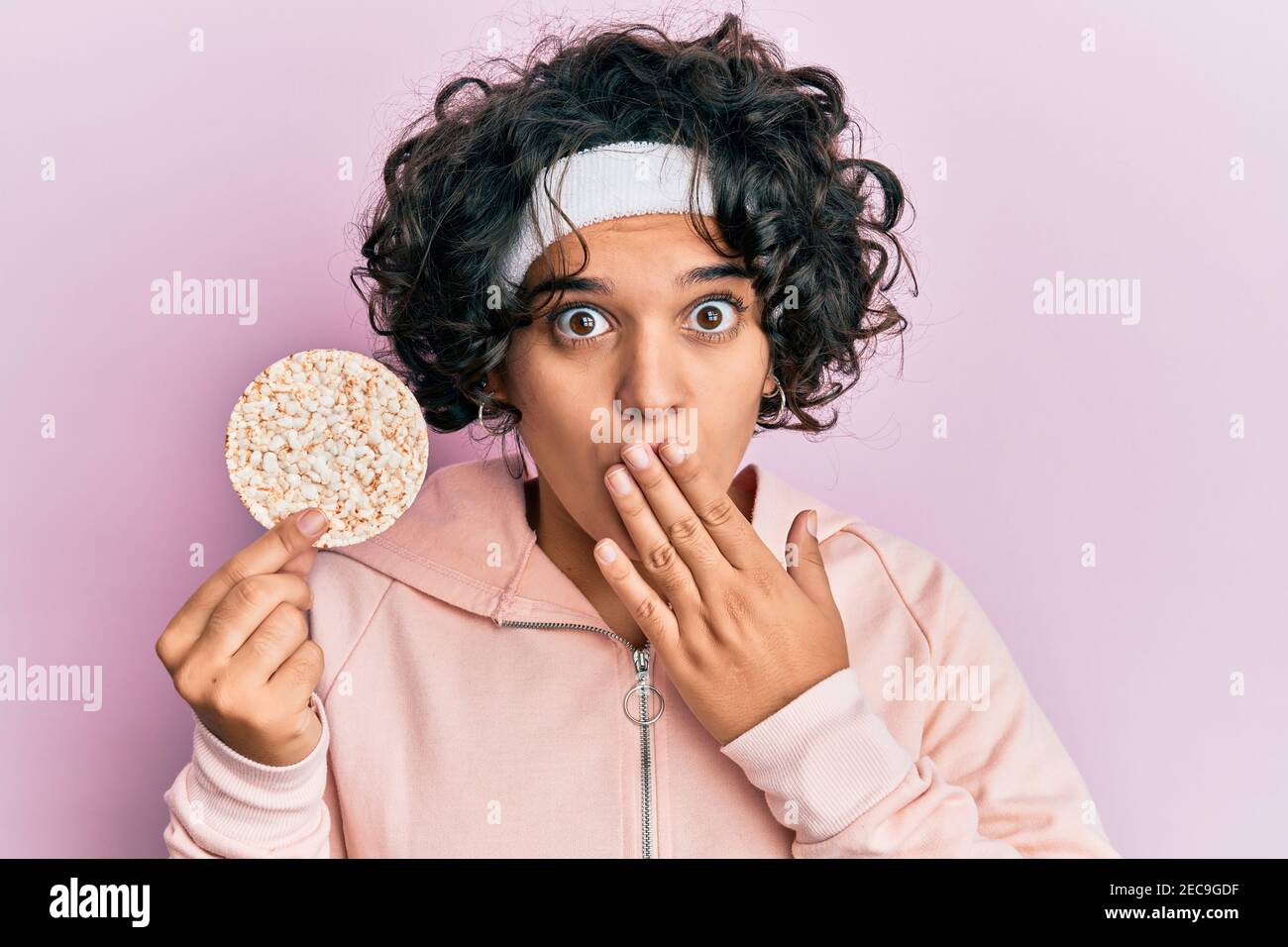 Young hispanic woman with curly hair eating healthy rice crackers ...