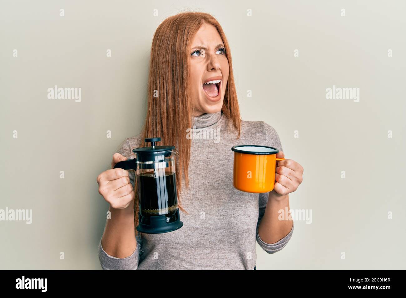Young irish woman drinking italian coffee angry and mad screaming ...