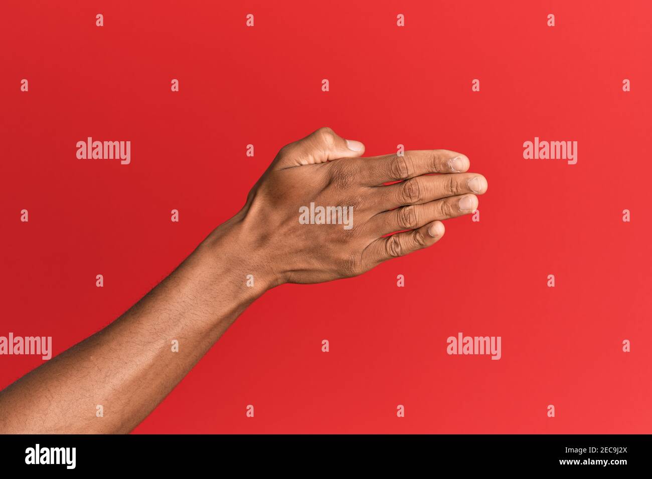 Hand of hispanic man over red isolated background stretching and ...
