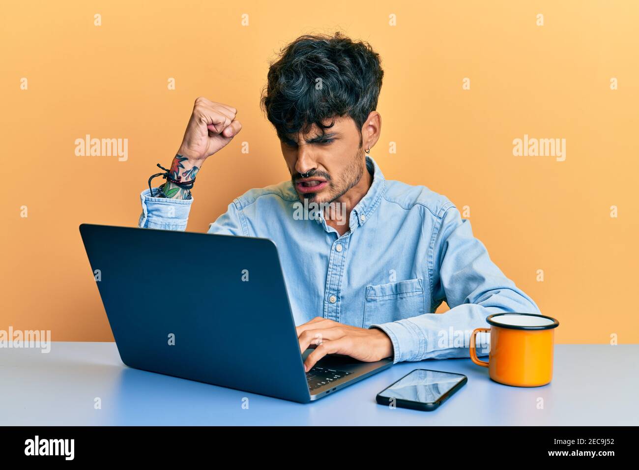 Young hispanic man working at the office drinking a cup of coffee ...