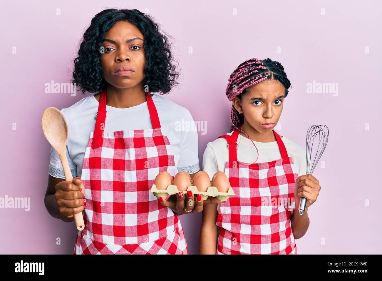 Beautiful african american mother and daughter cooking cake using baker ...