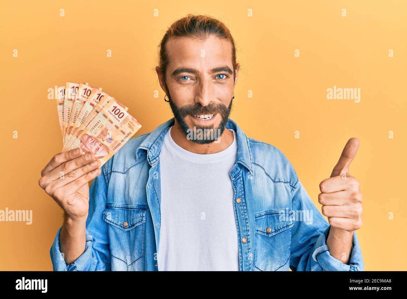 Attractive man with long hair and beard holding 100 mexican pesos ...