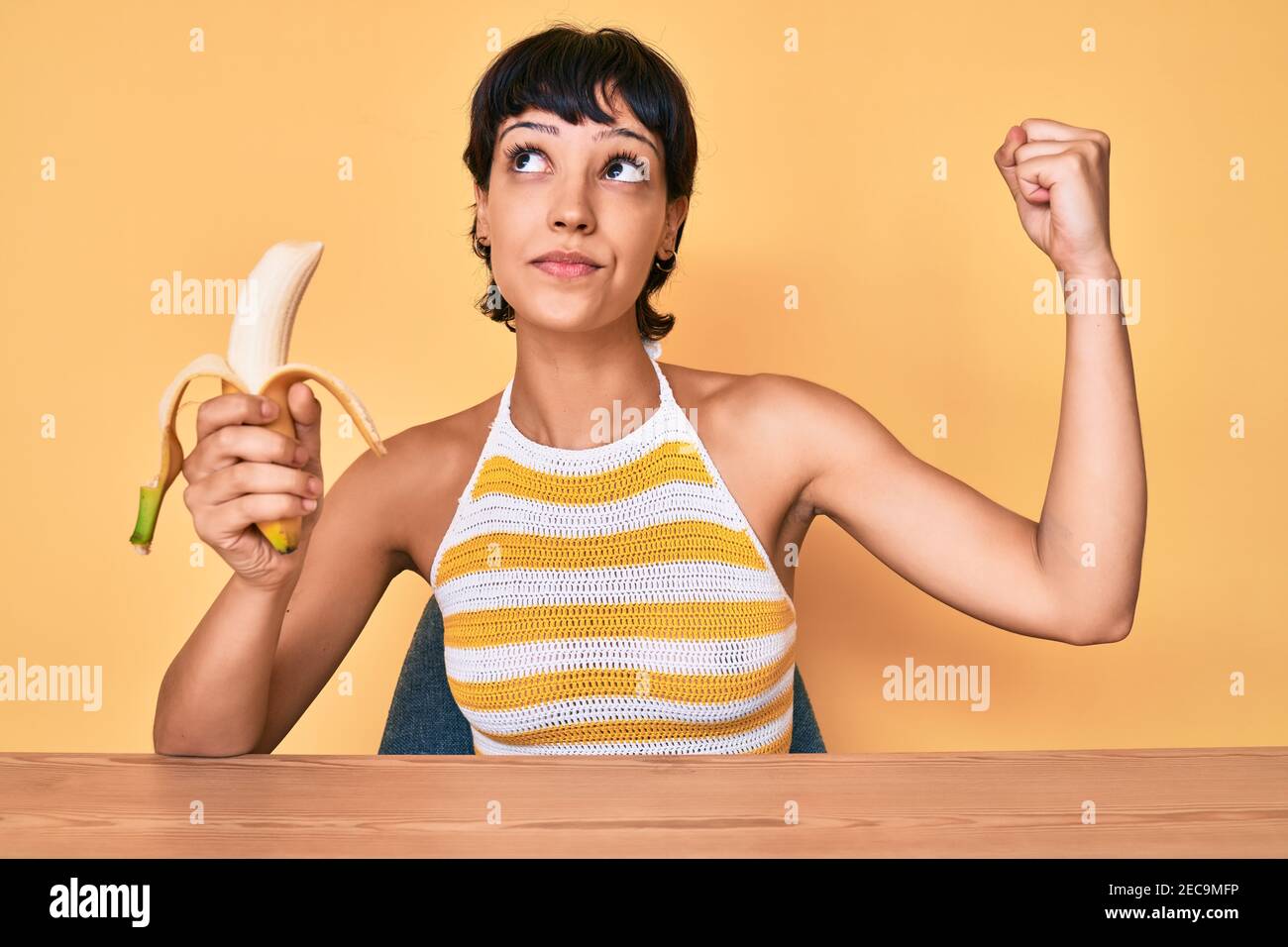 Brunette teenager girl eating banana as healthy snack smiling looking ...