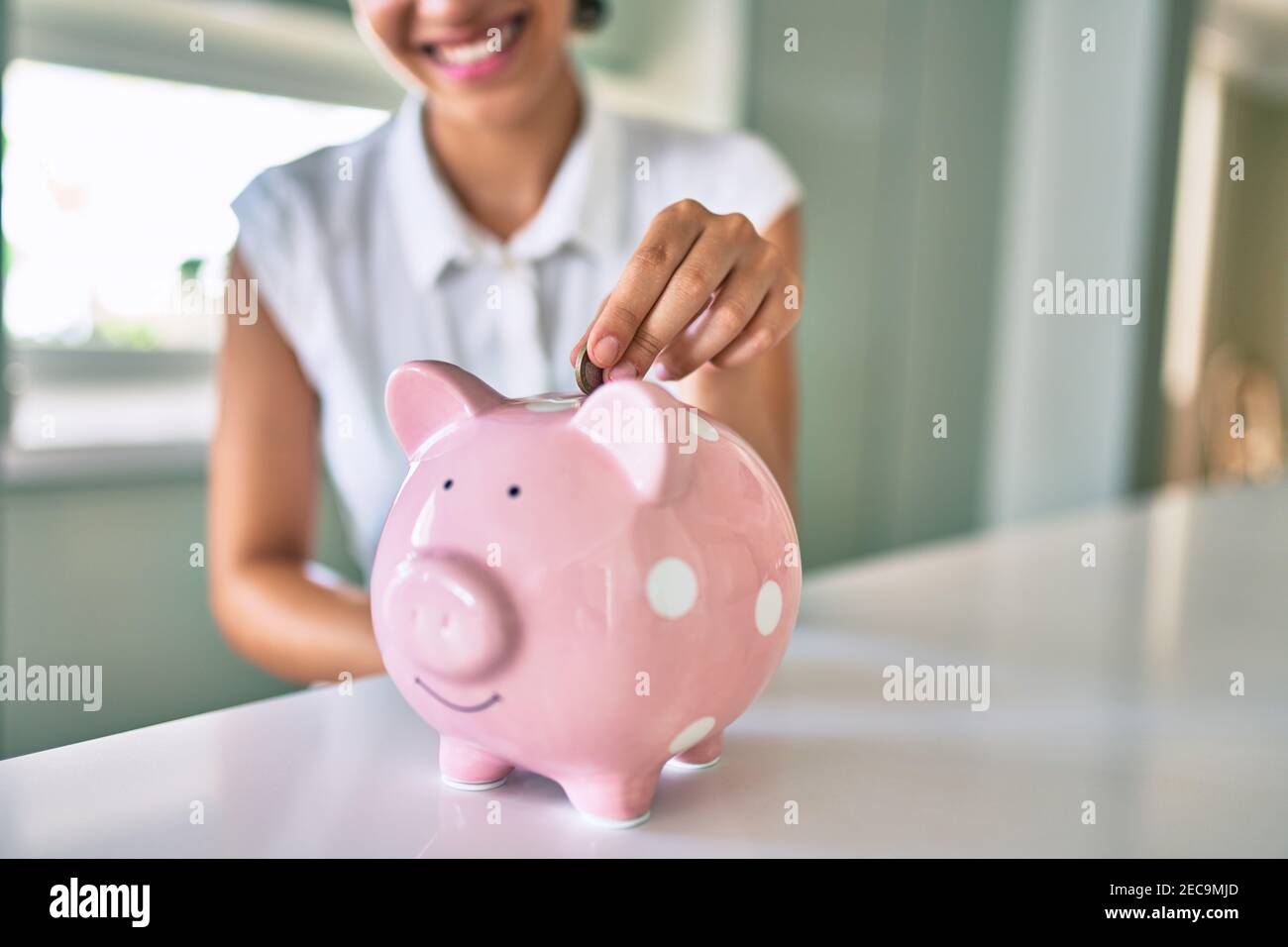 Young brunette woman smiling happy putting money savings inside of ...
