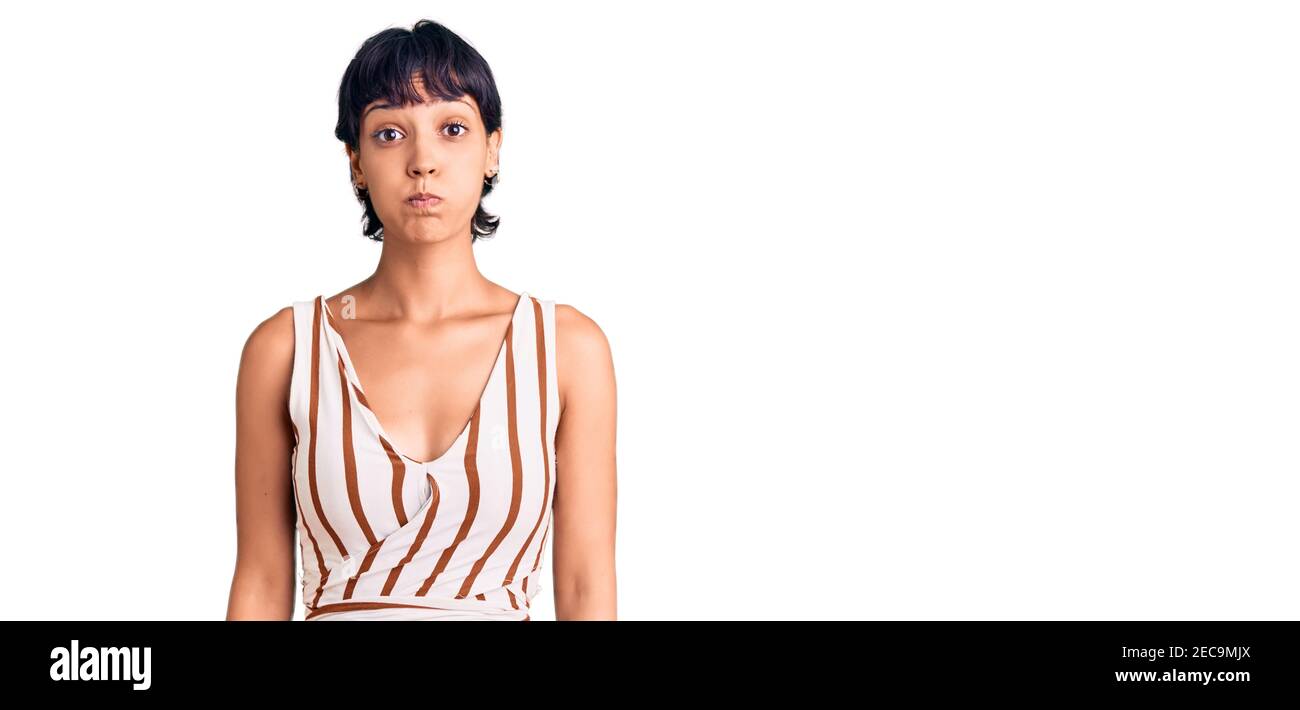 Young brunette woman with short hair wearing summer outfit puffing ...