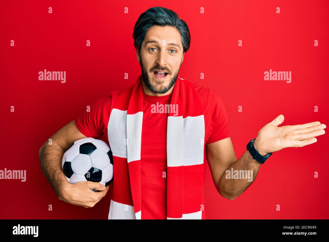 Young hispanic man football hooligan holding ball celebrating ...