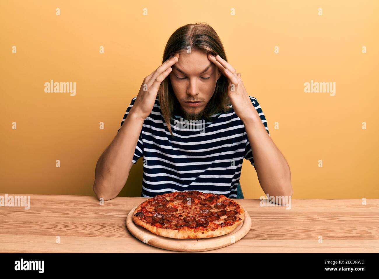 Handsome caucasian man with long hair eating tasty pepperoni pizza ...