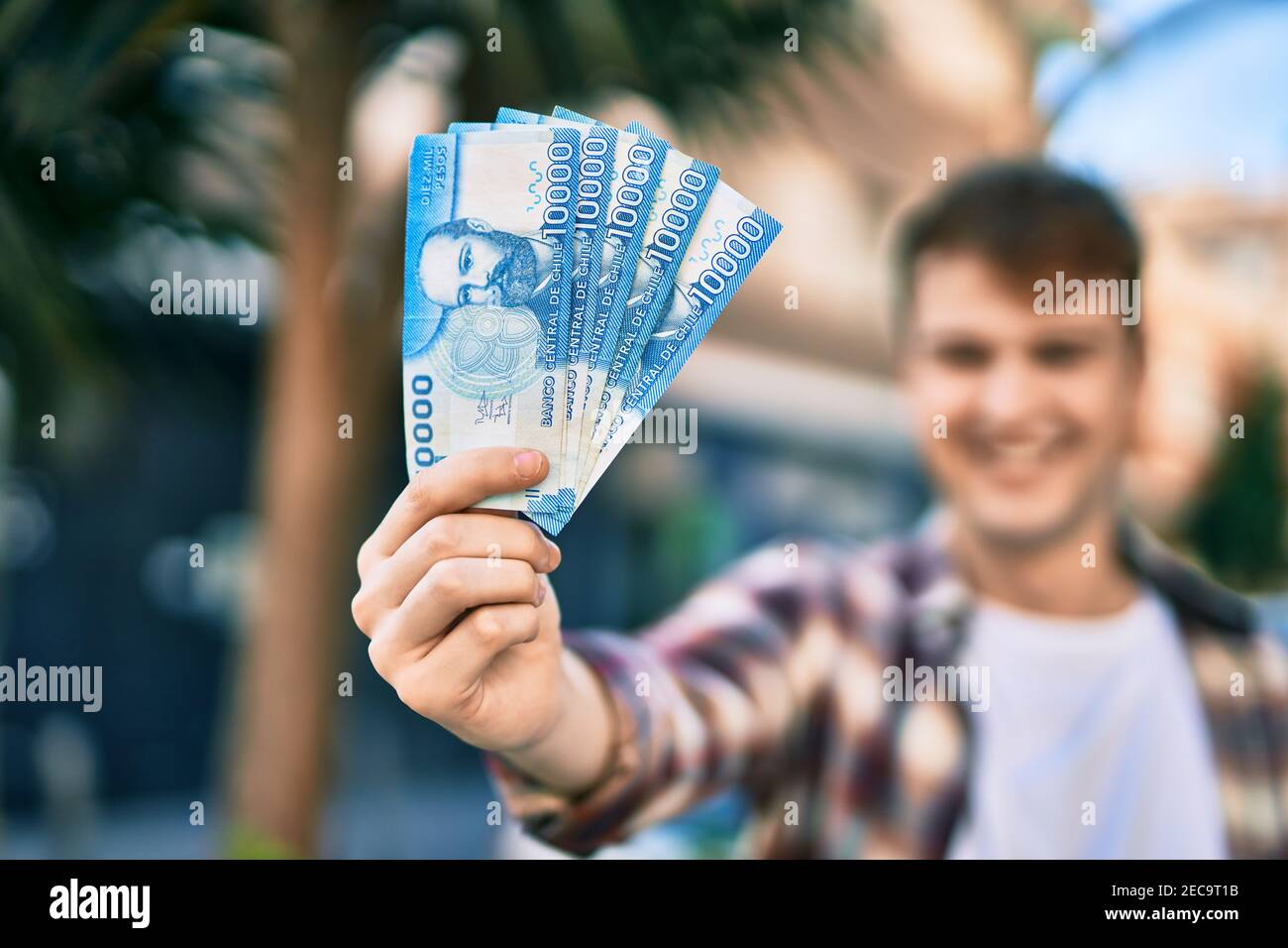 Young caucasian man smiling happy holding chile pesos banknotes at the ...