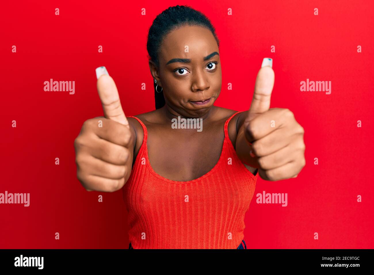 Young african american woman doing thumbs up positive gesture skeptic ...