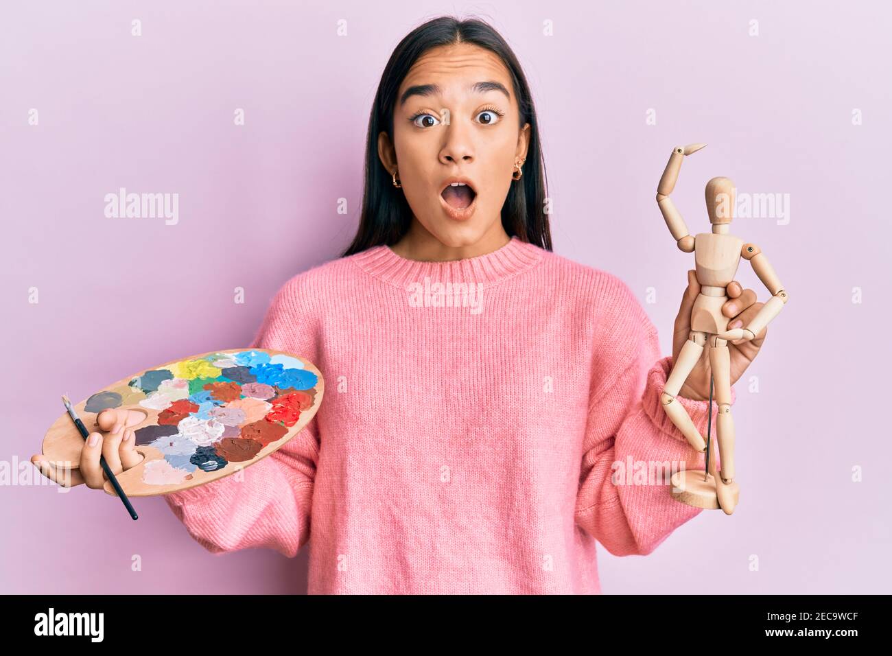 Young asian woman holding painter palette and art manikin afraid and ...