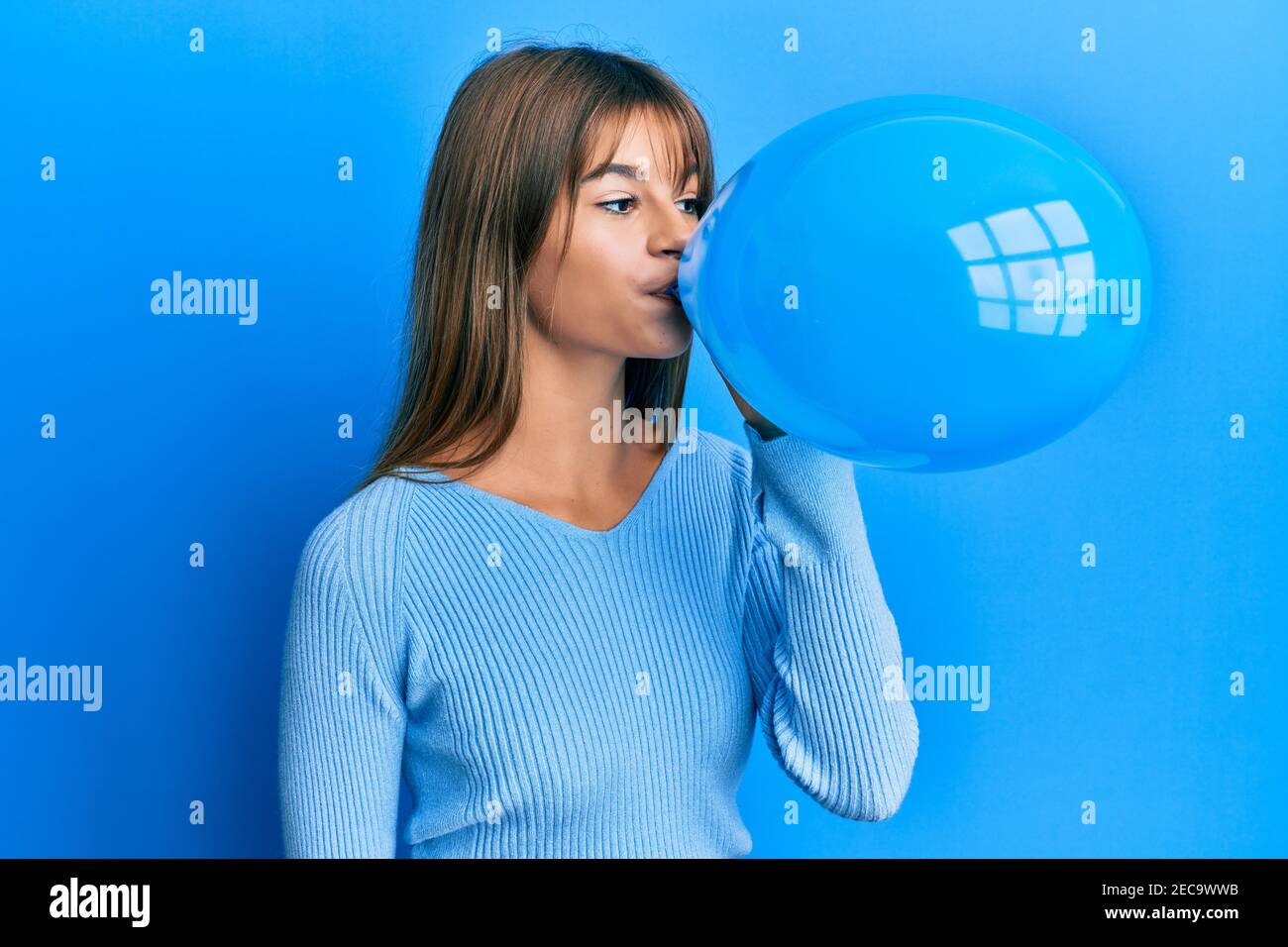 Caucasian woman blowing a balloon over blue background Stock Photo - Alamy