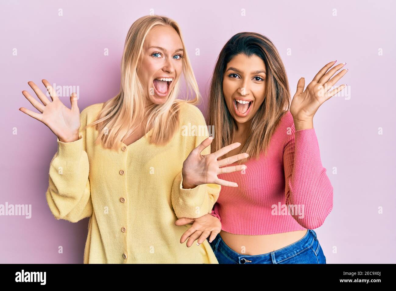 Two friends standing together over pink background celebrating crazy ...