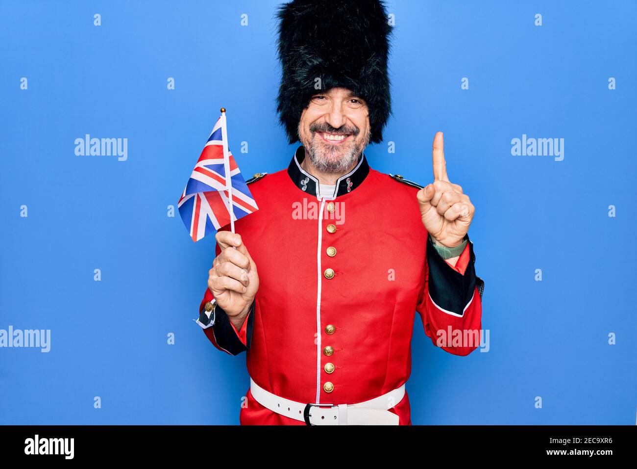 Middle age handsome wales guard man wearing traditional uniform holding ...