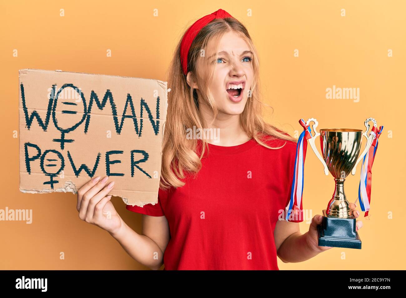 Beautiful young caucasian girl holding woman power banner and trophy ...