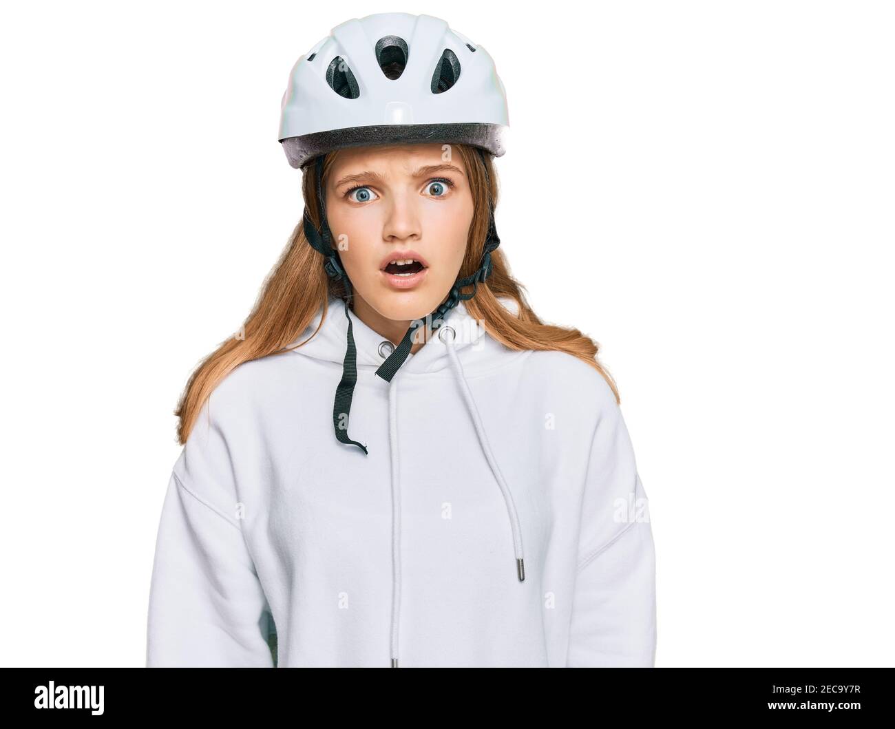 Beautiful young caucasian girl wearing bike helmet scared and amazed ...