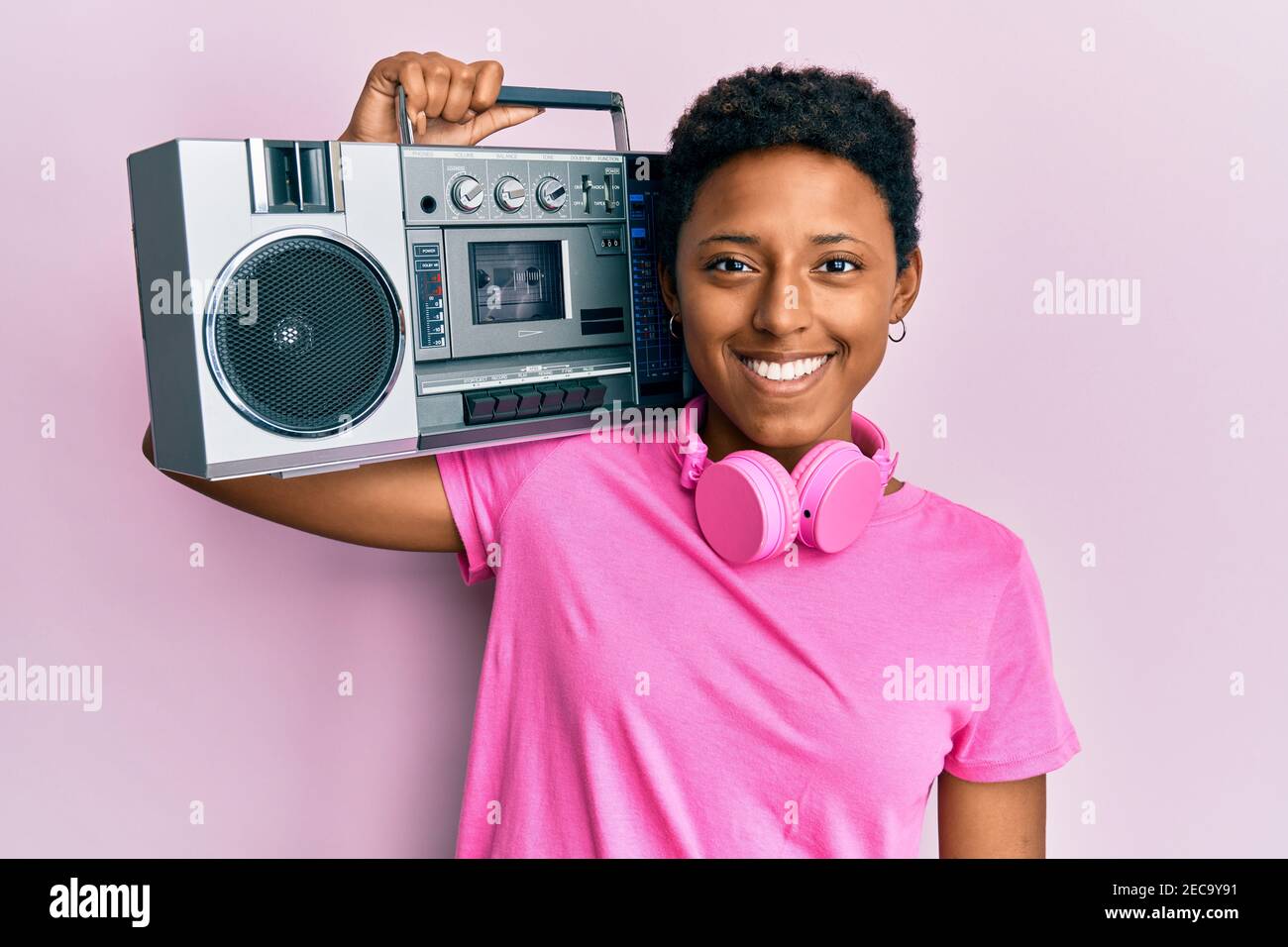 Young african american girl holding boombox, listening to music looking ...