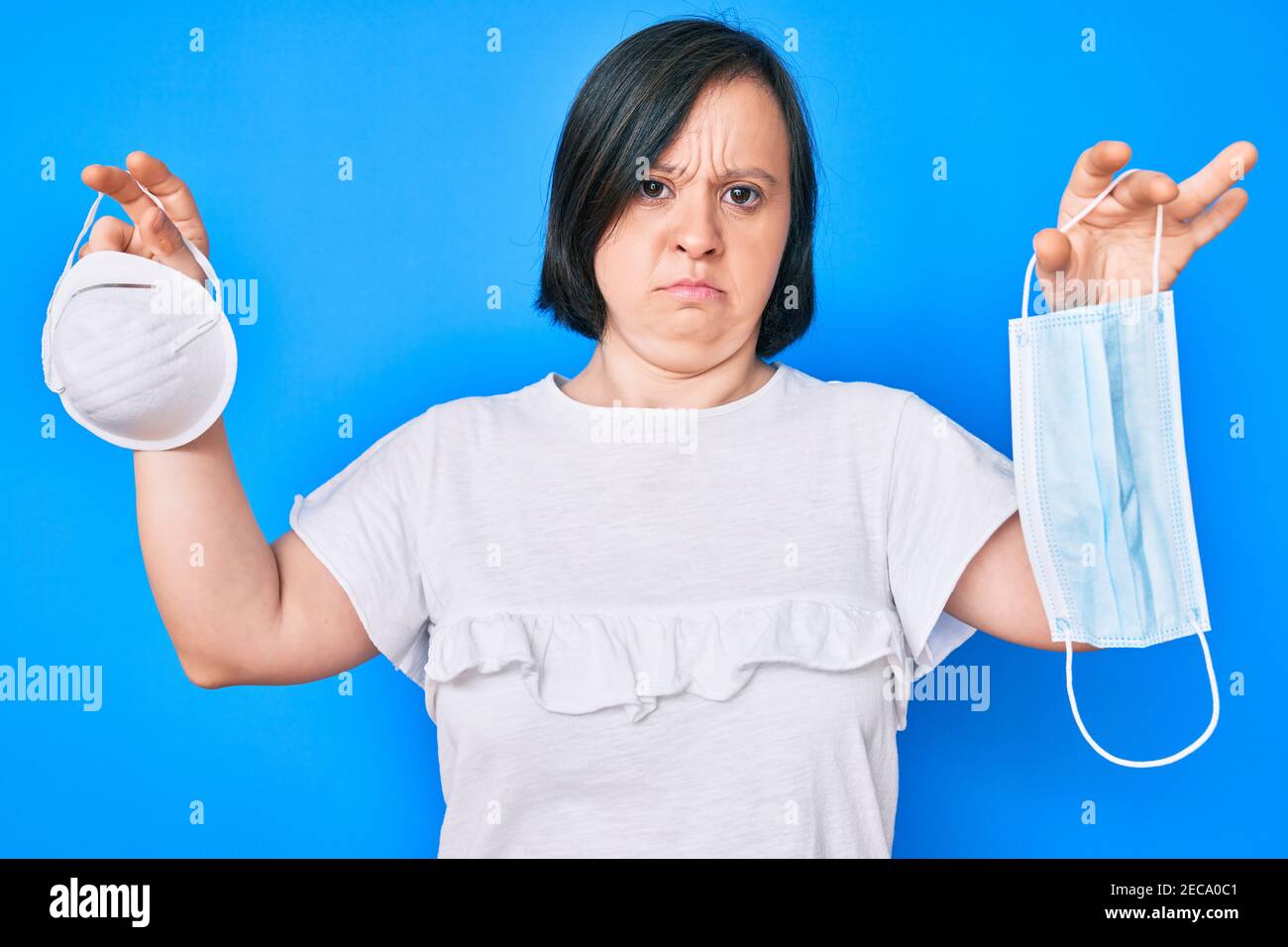 Brunette woman with down syndrome holding two different safety masks ...