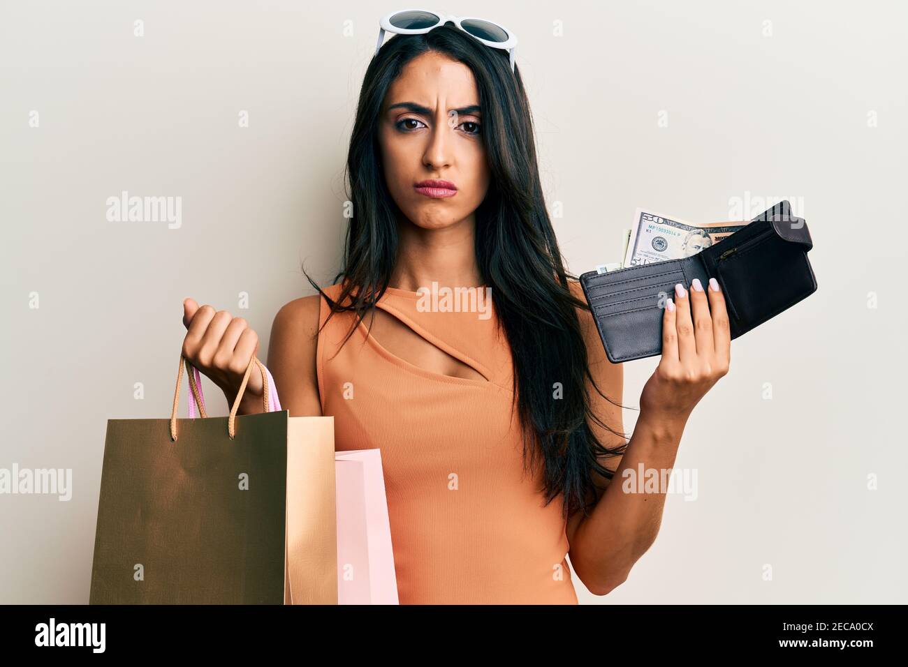 Beautiful hispanic woman holding shopping bags and wallet with dollars ...