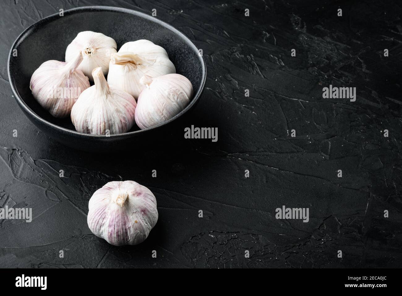 Pile of organic farm garlic set, in bowl, on black background , with ...