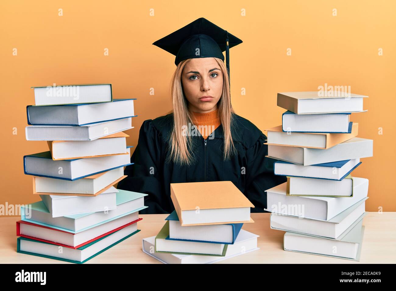 Young caucasian woman wearing graduation ceremony robe sitting on the ...
