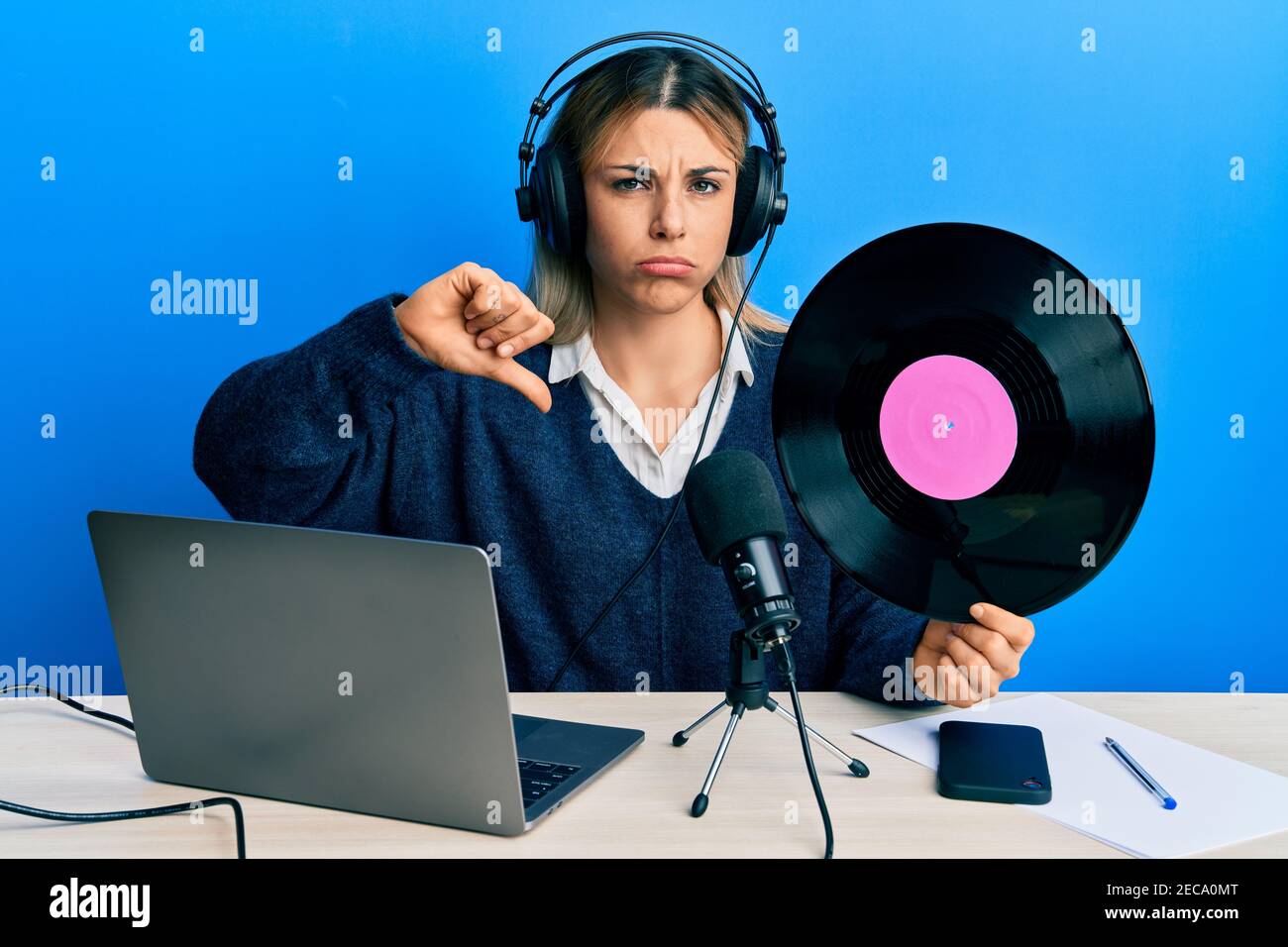 Young caucasian woman working at radio studio holding vinyl disc with ...