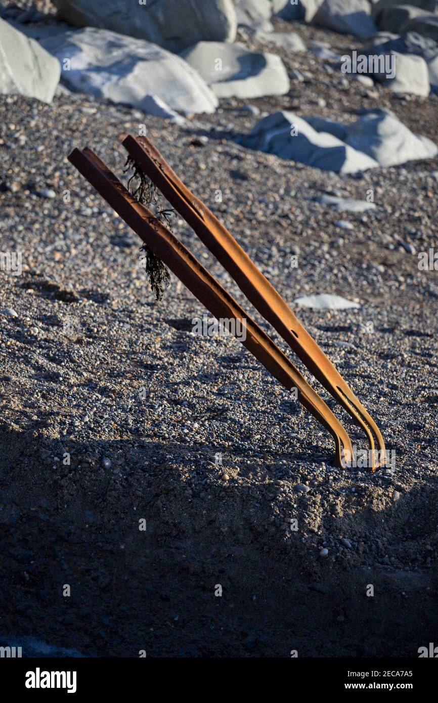 Beach with stacked limestone, pebbles and rusty metal frame in ...