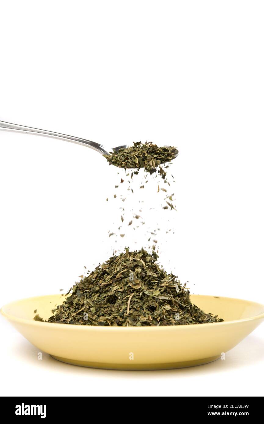 Heap and spoonful of dried herb on white Stock Photo - Alamy