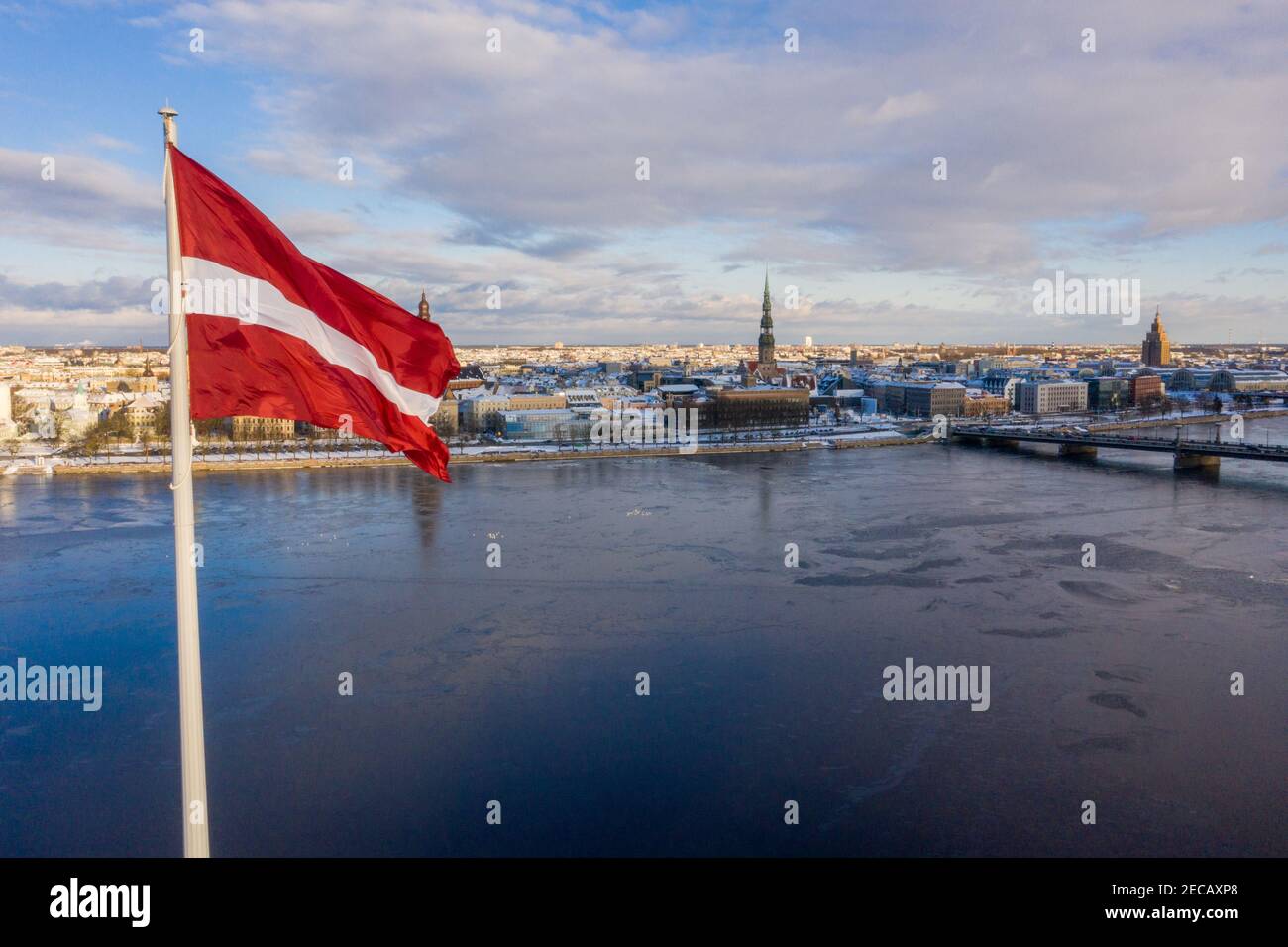 Flag of Latvia on a flagpole with the frozen Daugava River on the ...