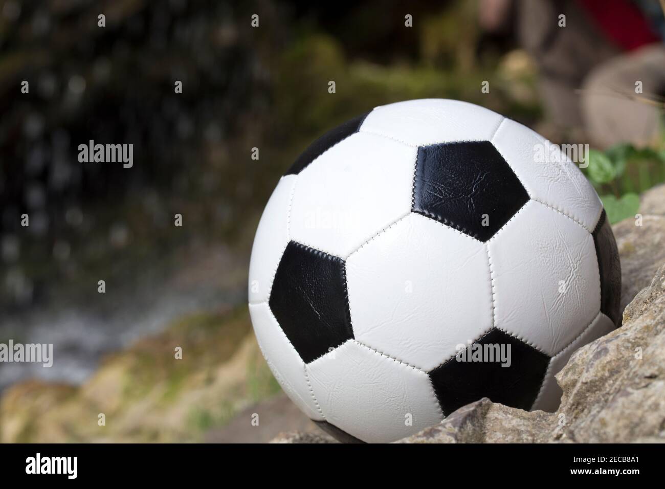 Football and the dark stone. Ball is situated on the rock. Background ...