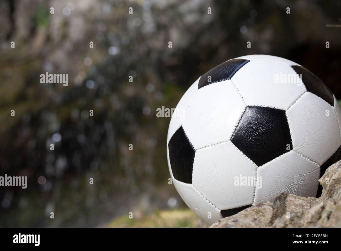 Football and the dark stone. Ball is situated on the rock. Background ...