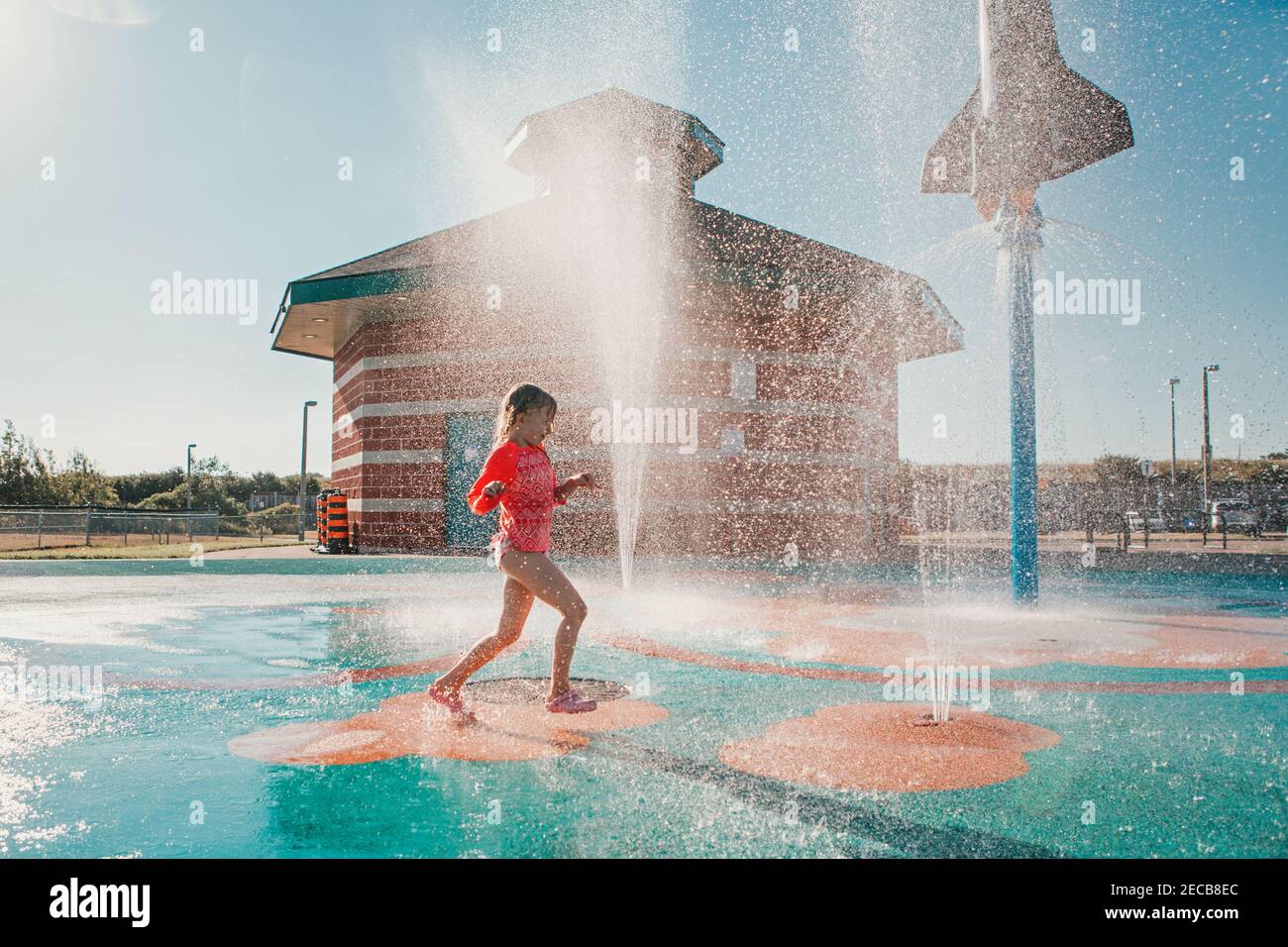 Cute adorable Caucasian funny girl playing on splash pad playground on ...