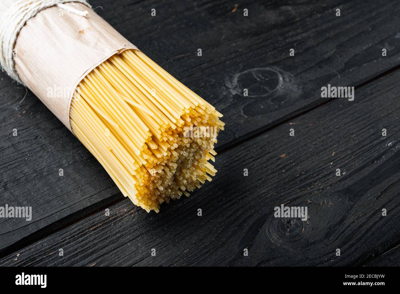 Long spaghetti. Raw spaghetti set, on black wooden table background ...