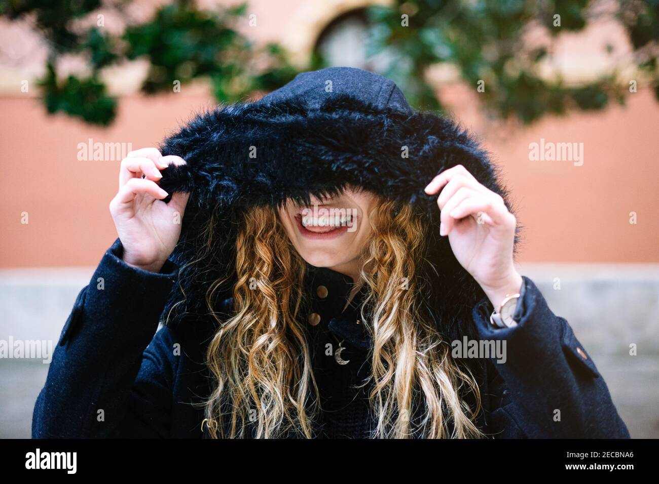 Young blonde woman with a hood over her head laughing merrily Stock ...